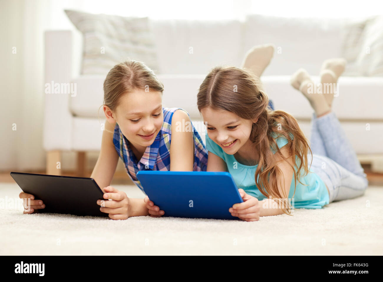 happy girls with tablet pc lying on floor at home Stock Photo - Alamy