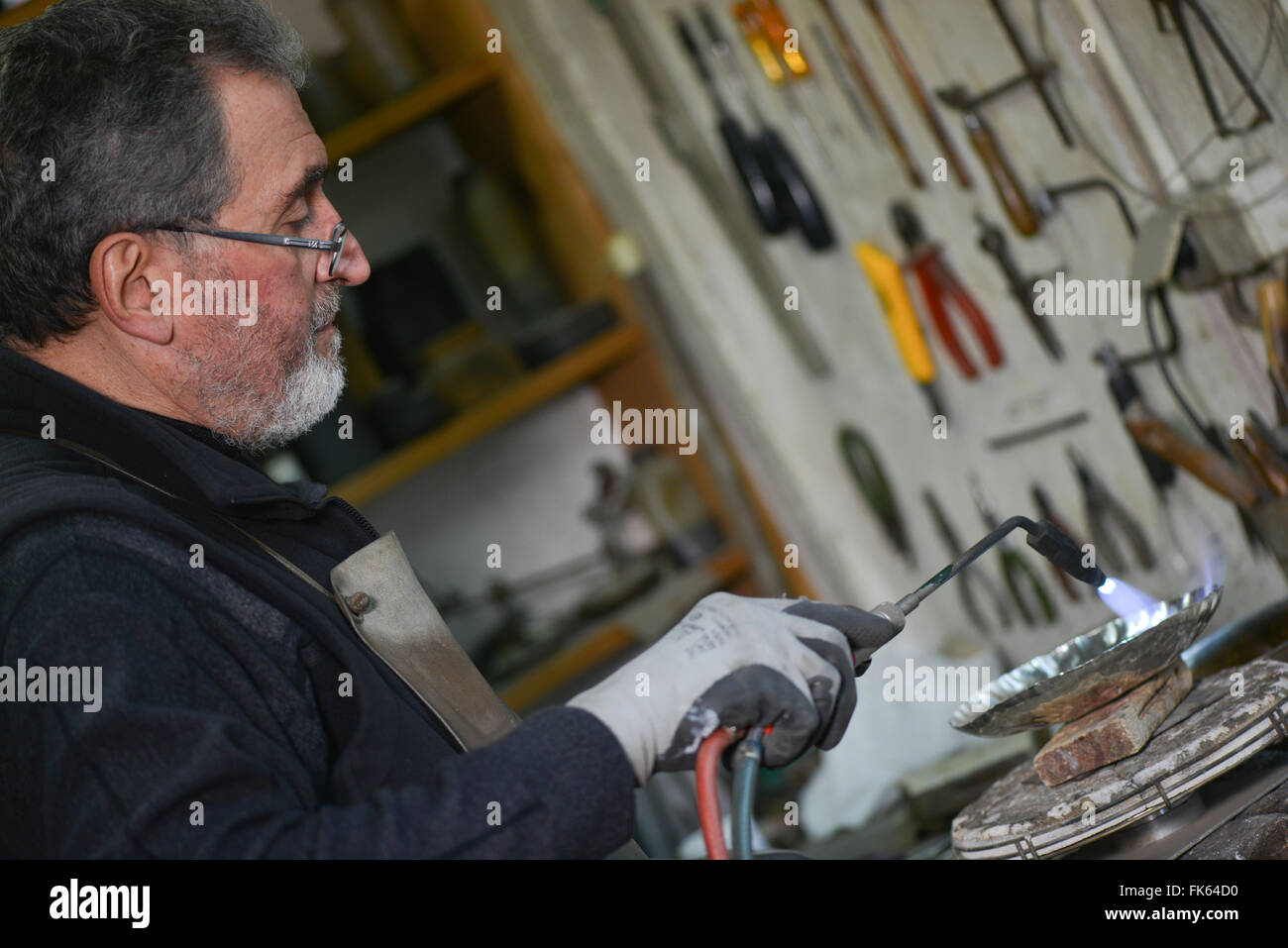 Master goldsmith working with silver-Annealing the metal to make it ...