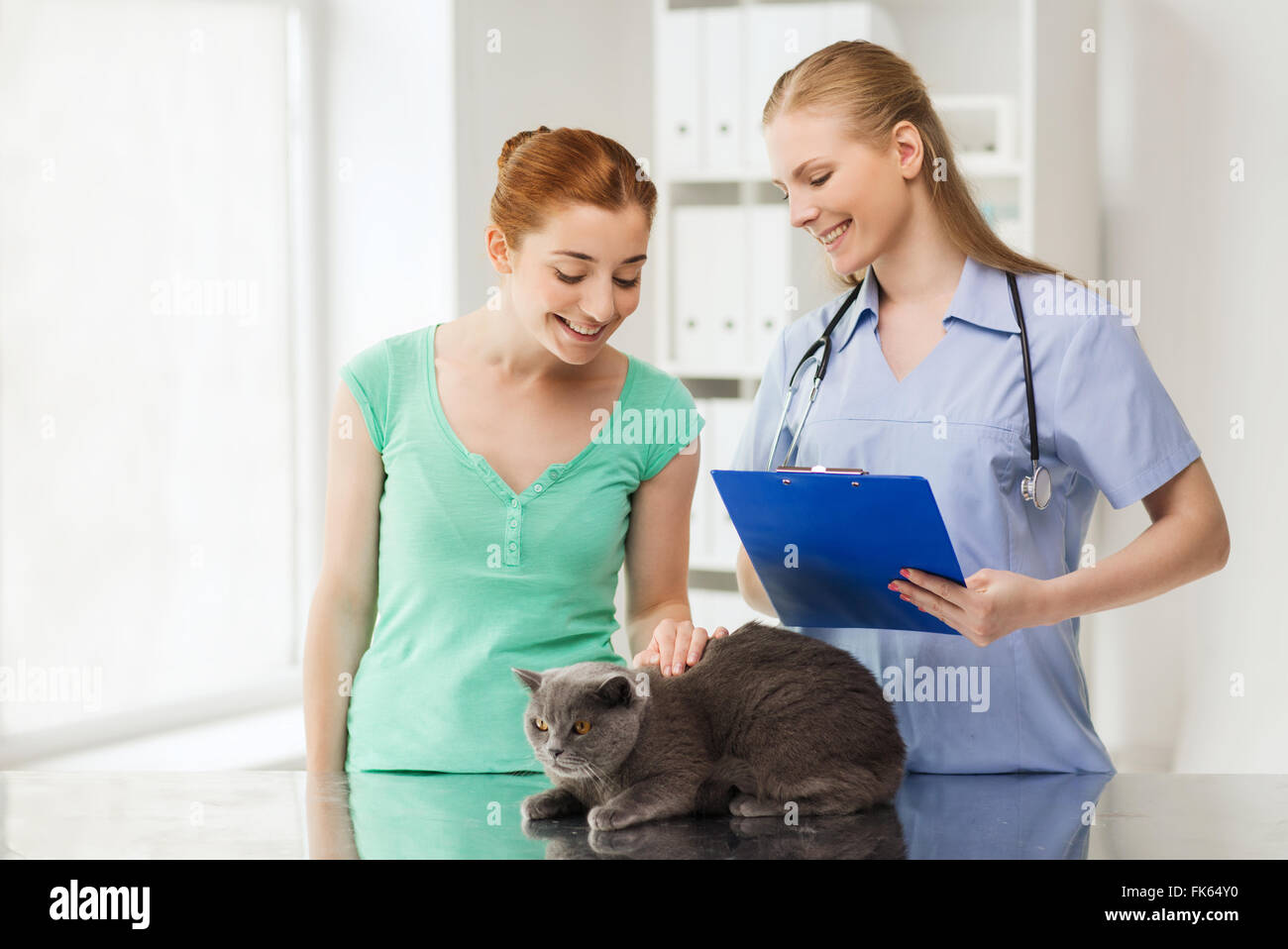 happy woman with cat and doctor at vet clinic Stock Photo - Alamy