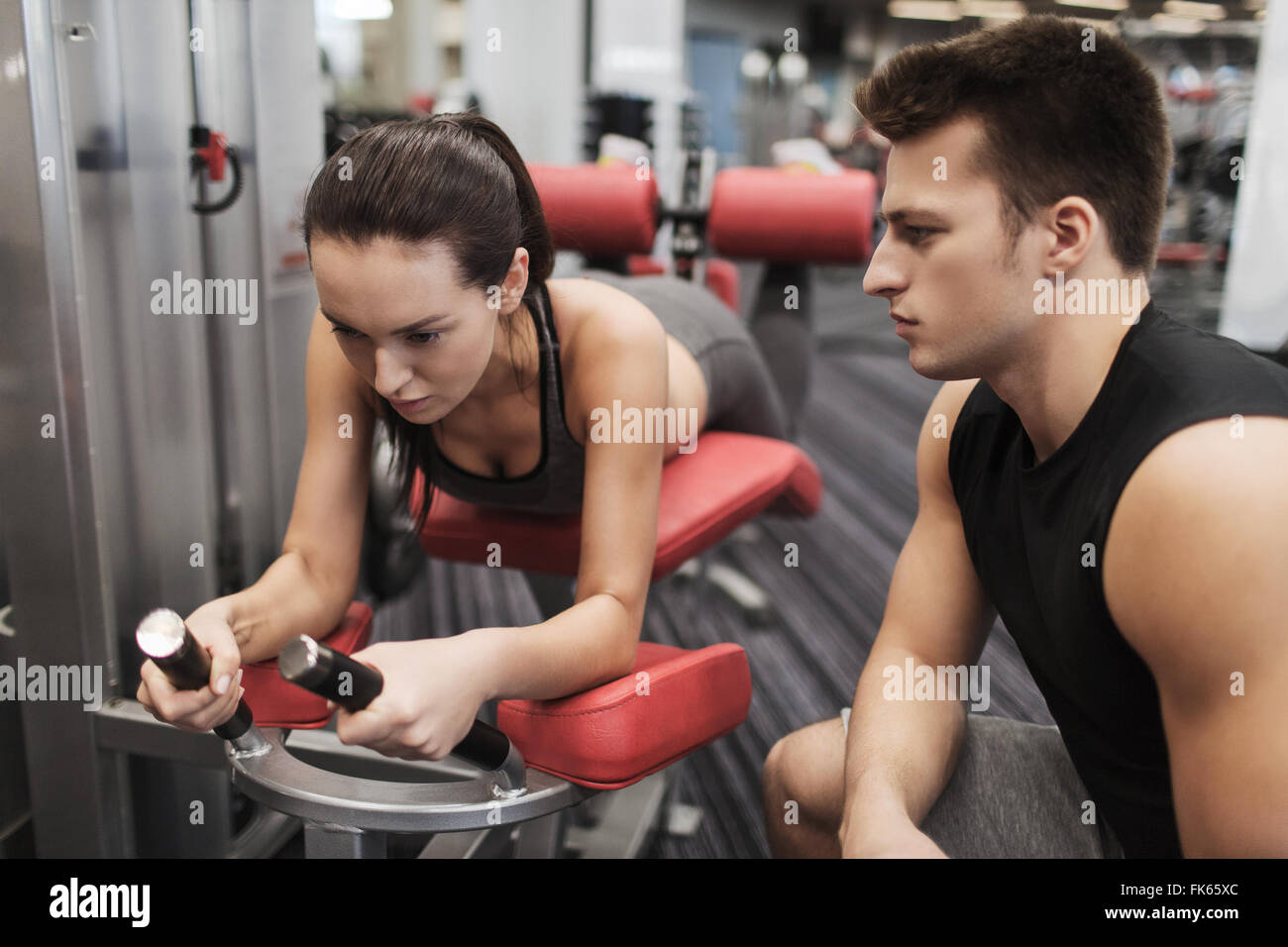 young woman with trainer exercising on gym machine Stock Photo - Alamy