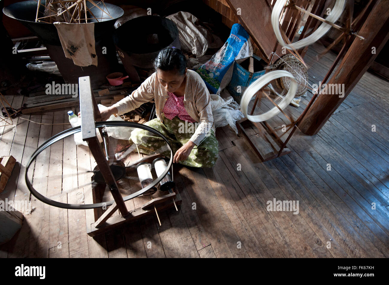Woman spinning silk thread on a spinning wheel with bicycle wheel, Ko ...