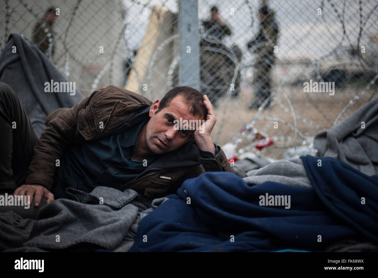 A migrant waits for the opening of the Macedonian checkpoint near the ...