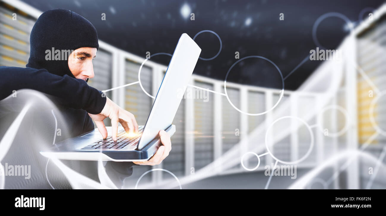 Composite image of burglar hacking a laptop and looking behind him ...