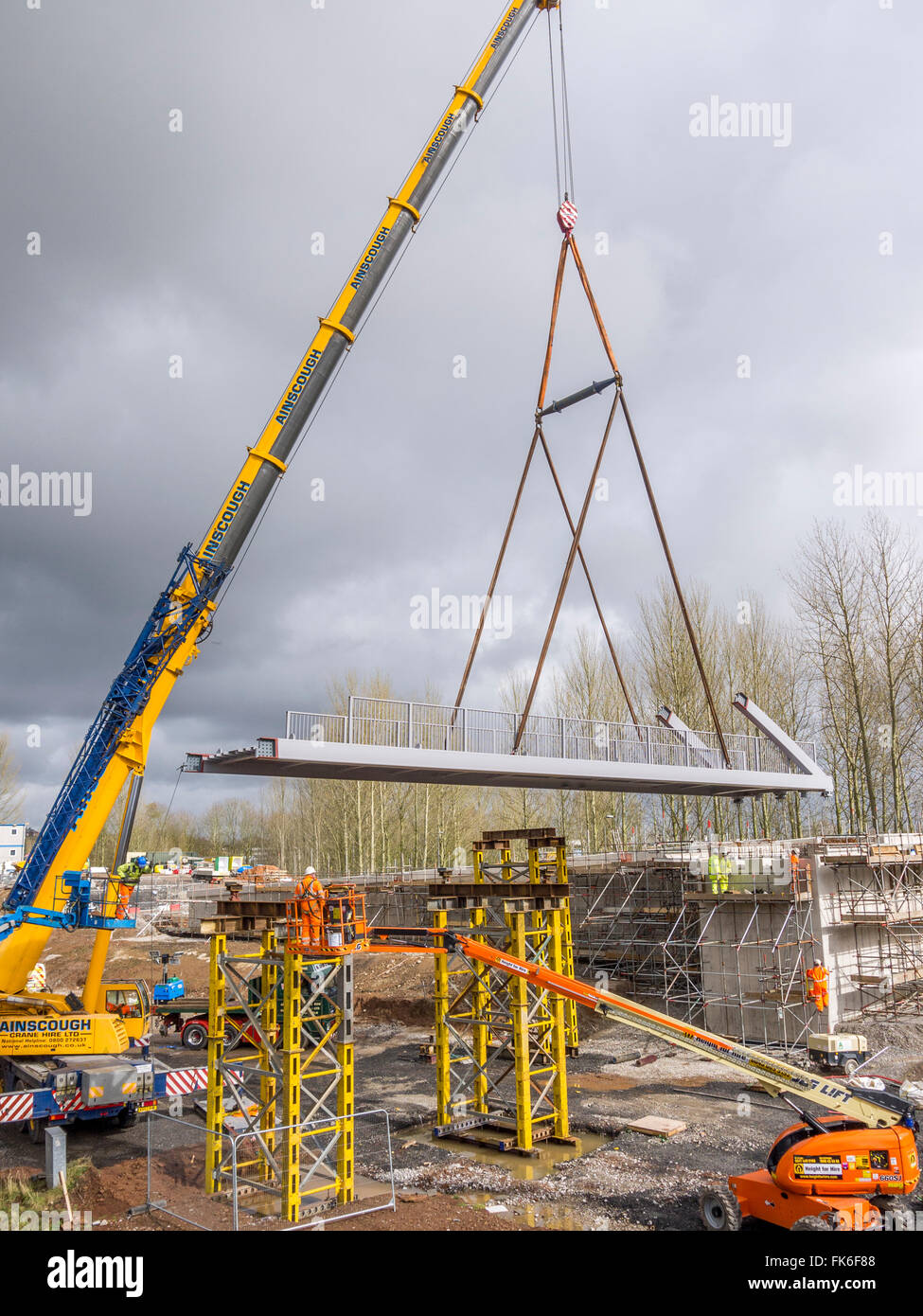 Crane lifting a section of a footbridge in to place, with construction ...
