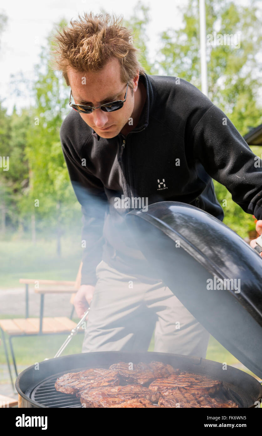 Man grilling meat outdoors Stock Photo - Alamy