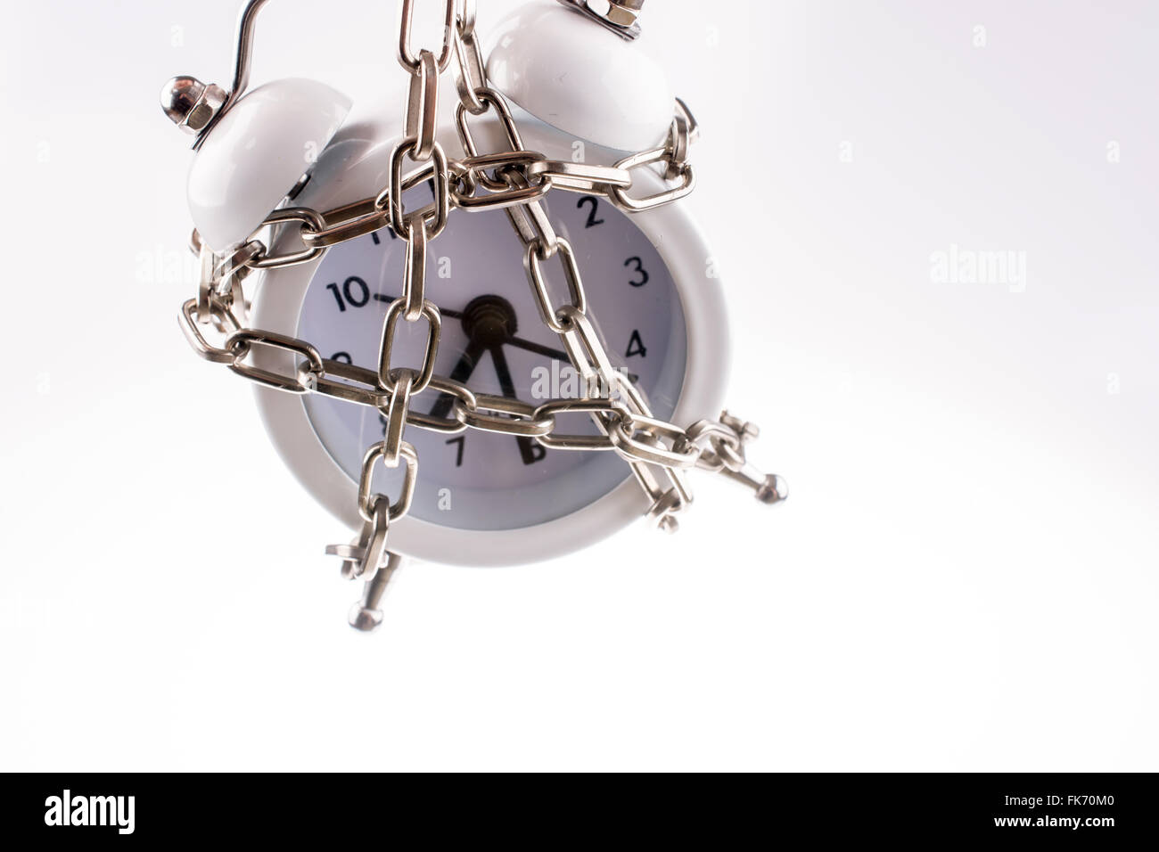 White color alarm clock in chain on a white background Stock Photo - Alamy