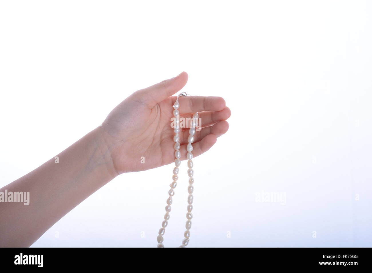 Hand holding a pearl necklace on a white background Stock Photo - Alamy