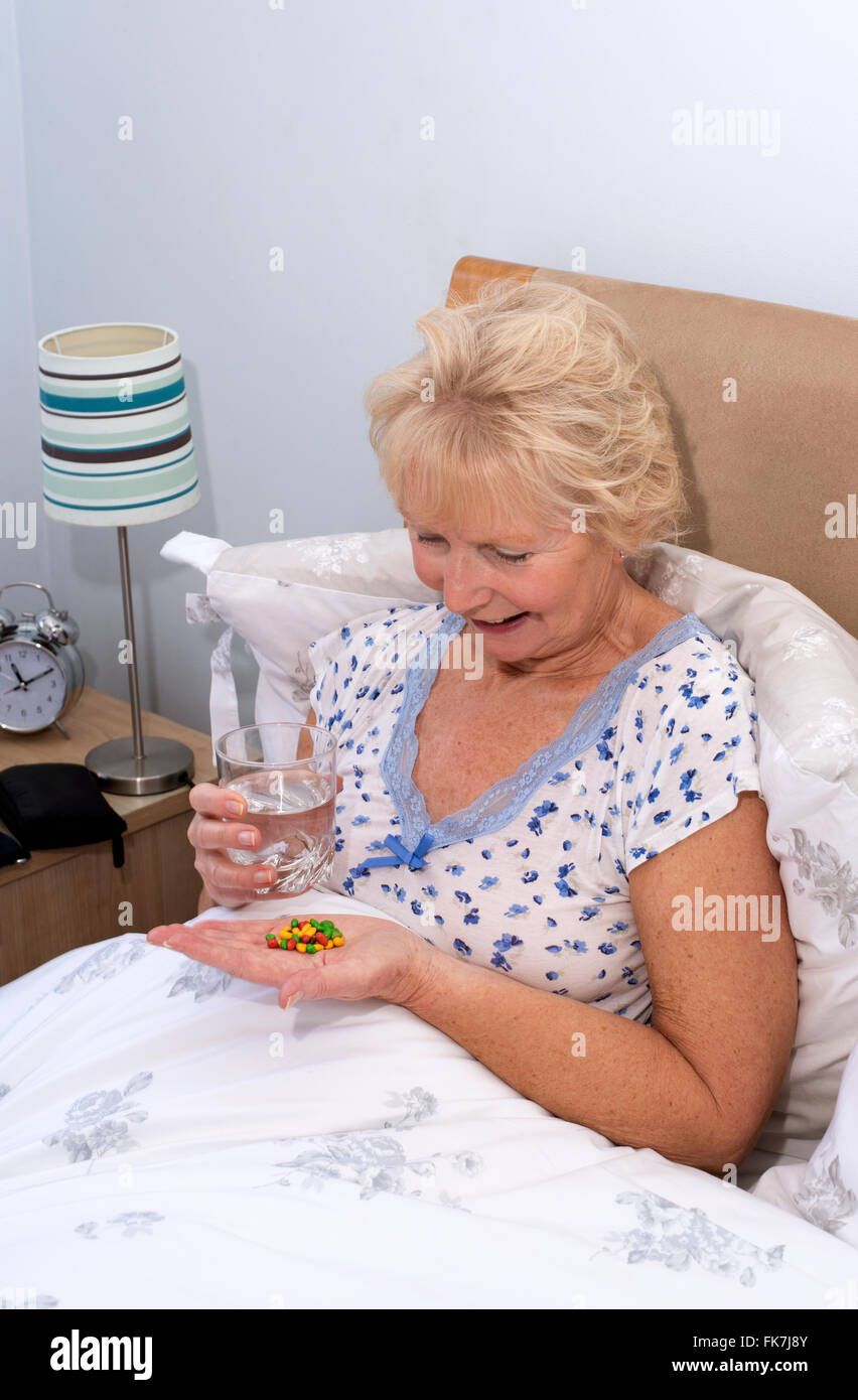 Elderly woman sitting in bed taking tablets at bedtime Stock Photo - Alamy