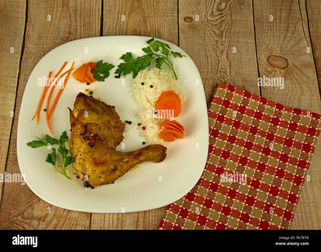 White plate with fried chicken leg,rice,decorative pieces of carrots ...