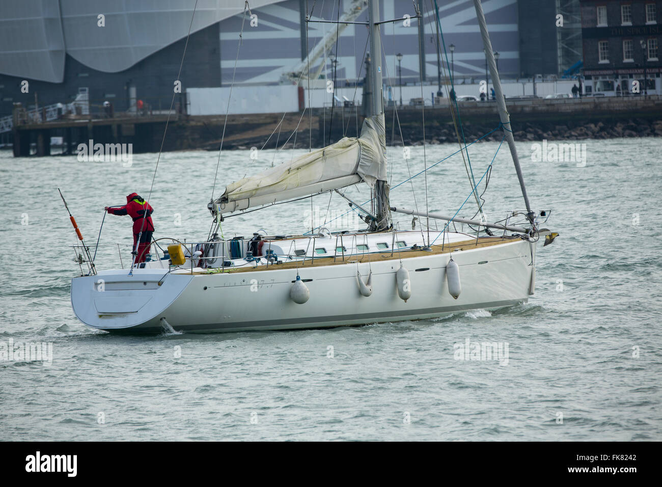 Small sailing craft with lone sailor adjusting the rigging. Boat ...