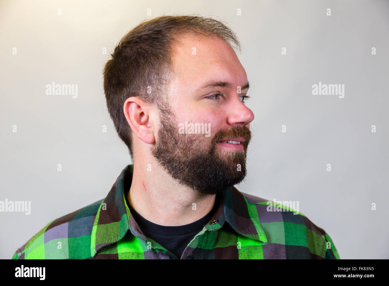 Man in his mid-30's poses for a studio portrait with a semi white ...