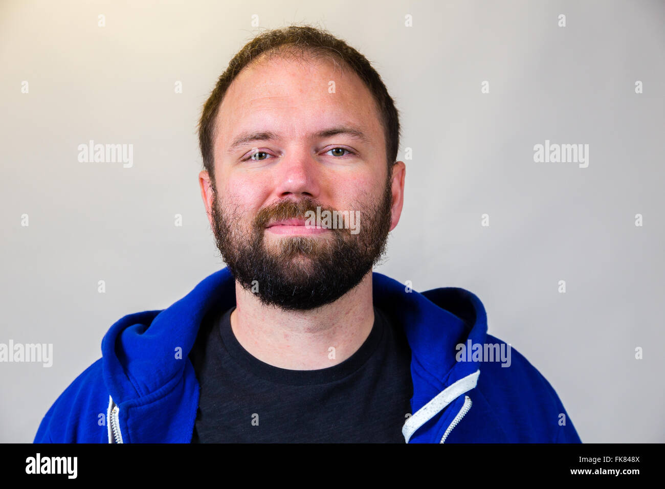 Man in his mid-30's poses for a studio portrait with a semi white ...
