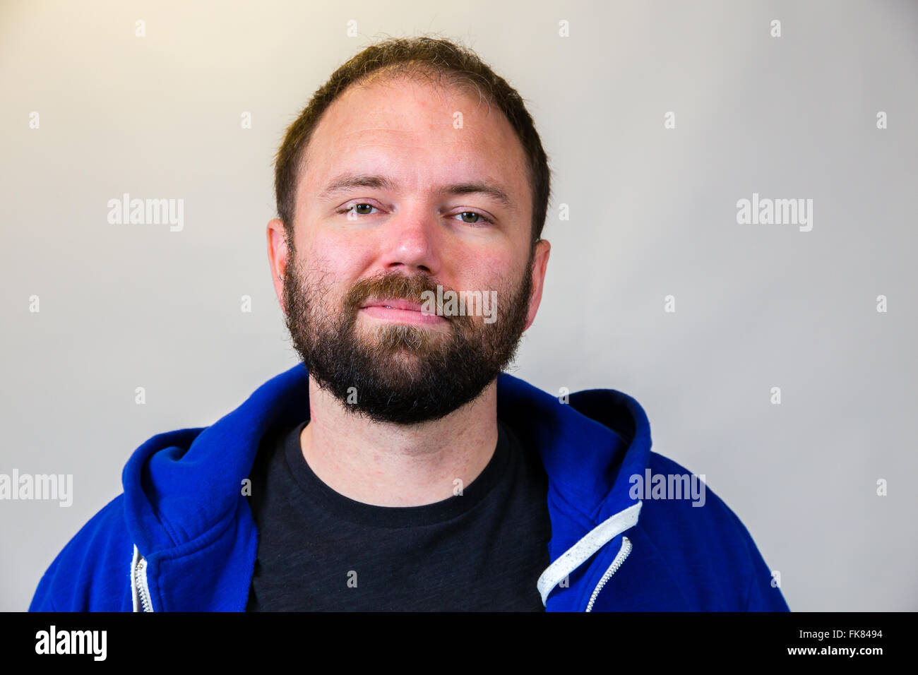 Man in his mid-30's poses for a studio portrait with a semi white ...