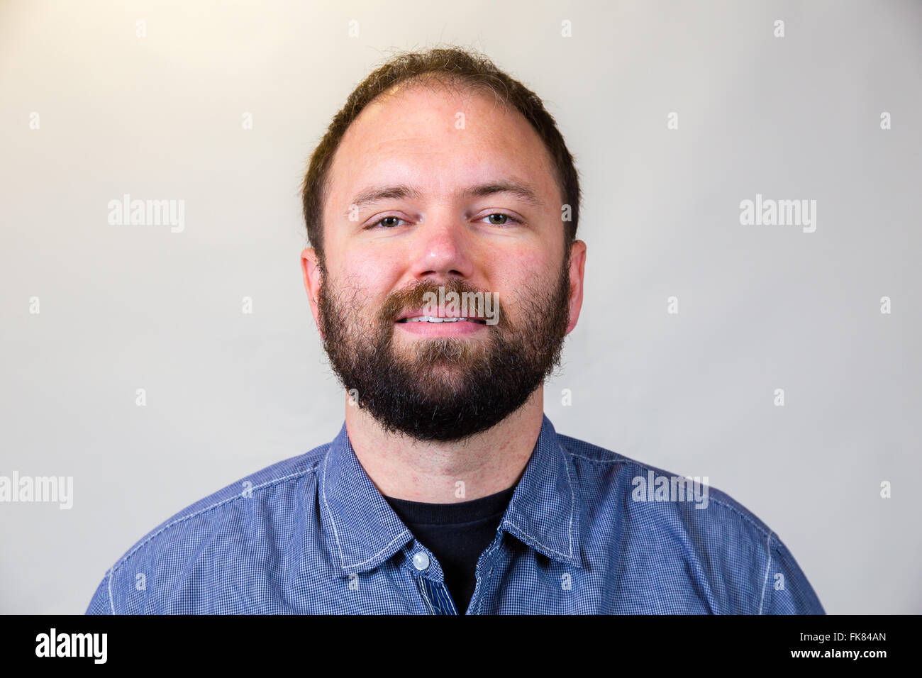 Man in his mid-30's poses for a studio portrait with a semi white ...