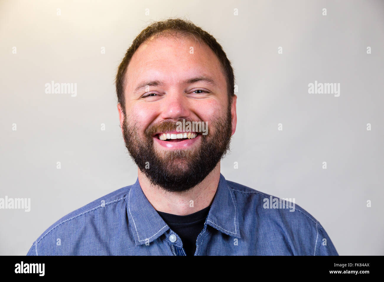 Man in his mid-30's poses for a studio portrait with a semi white ...
