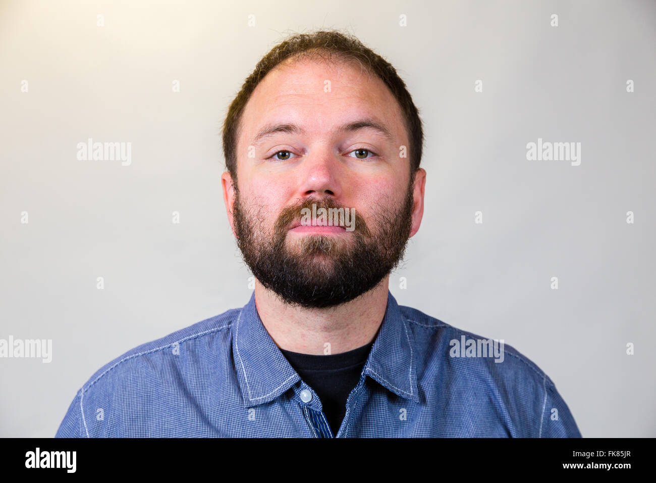 Man in his mid-30's poses for a studio portrait with a semi white ...