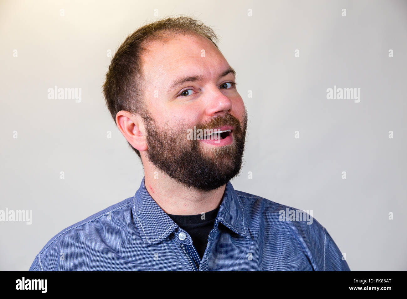 Man in his mid-30's poses for a studio portrait with a semi white ...