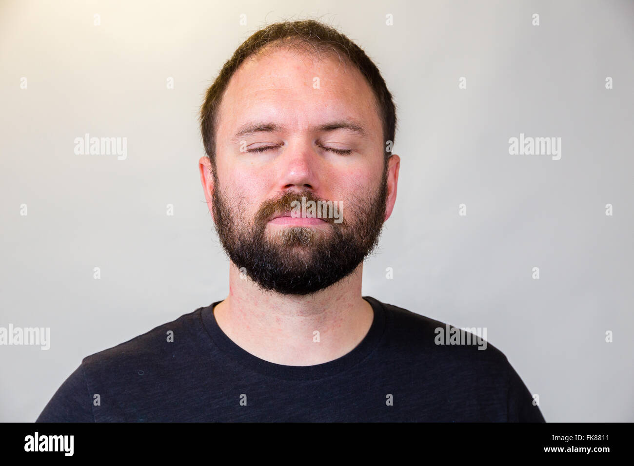 Man in his mid-30's poses for a studio portrait with a semi white ...