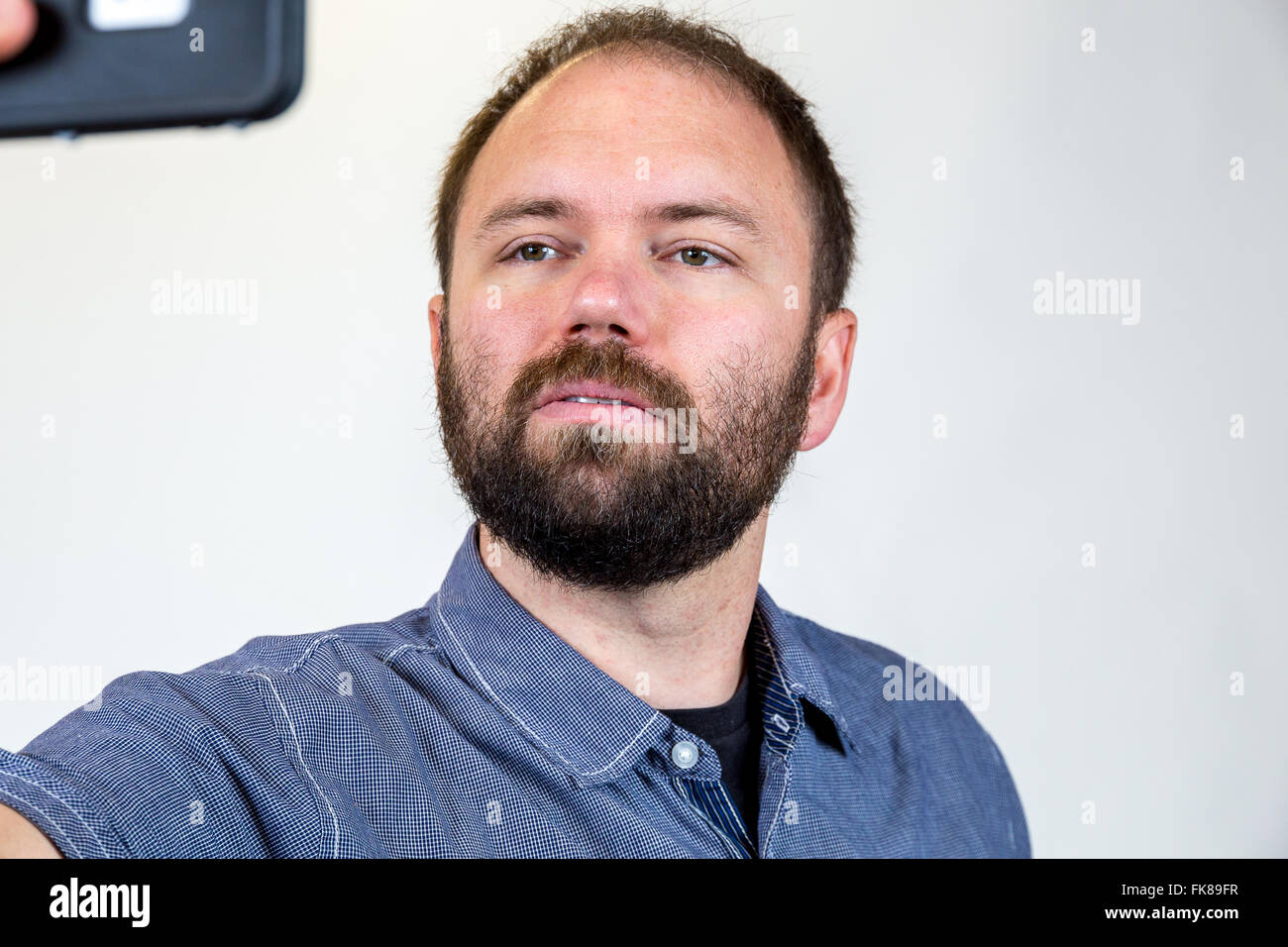 Man in his mid-30's poses for a studio portrait with a semi white ...