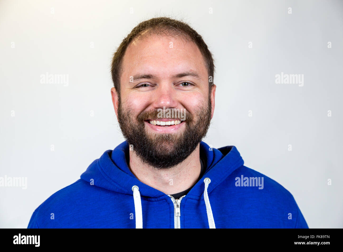 Man in his mid-30's poses for a studio portrait with a semi white ...