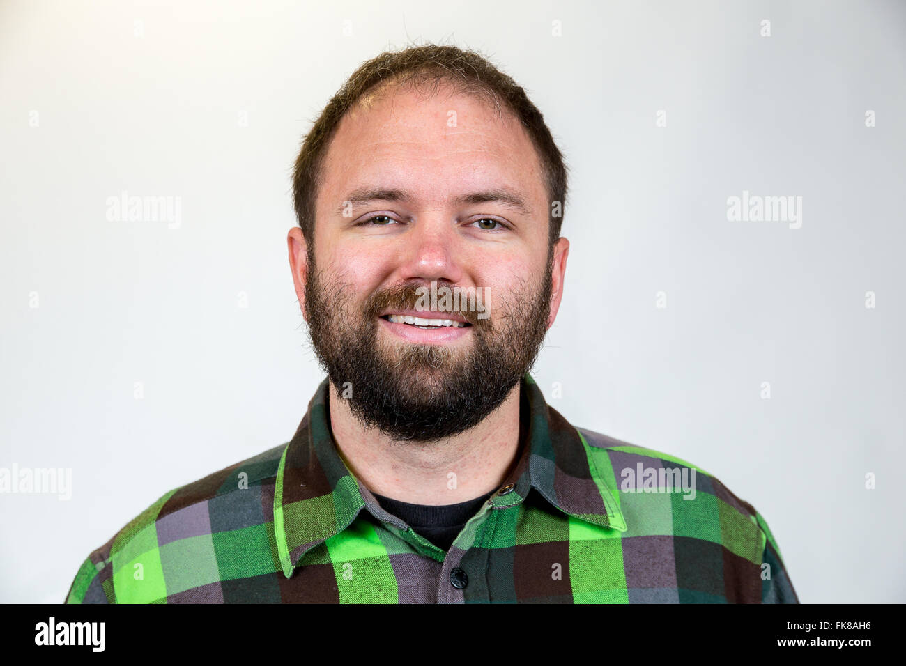 Man in his mid-30's poses for a studio portrait with a semi white ...