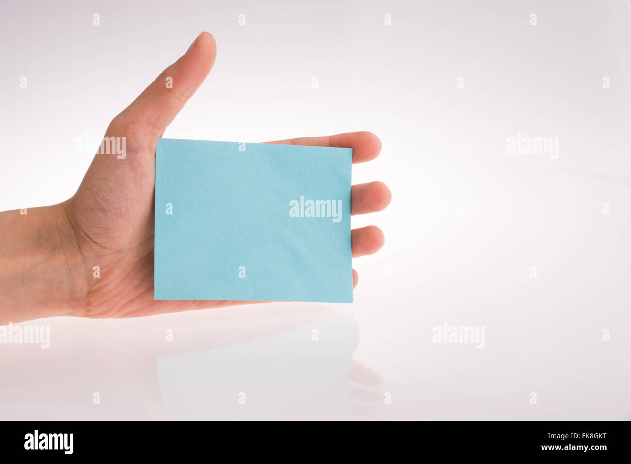 Hand holding a light blue color rectangular paper on a white background ...