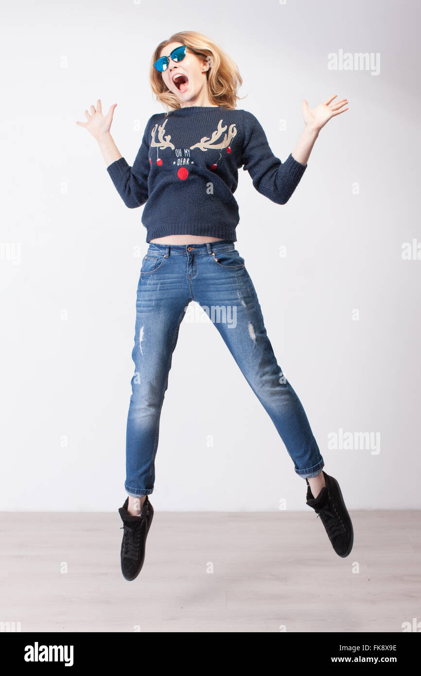 beautiful caucasian girl in jeans and glasses jumps and laughs, delight ...