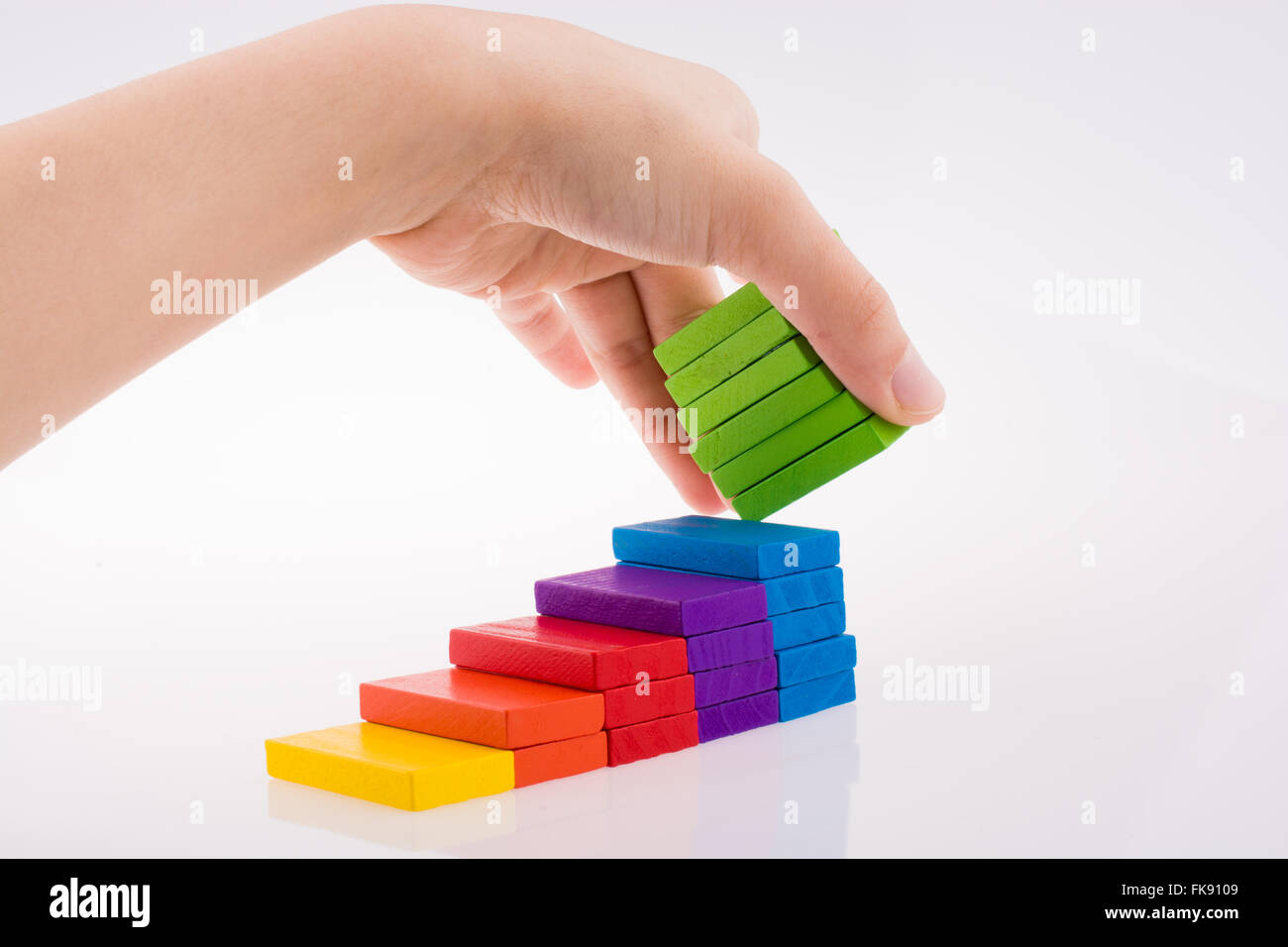 Hand playing with colored domino on white background Stock Photo - Alamy