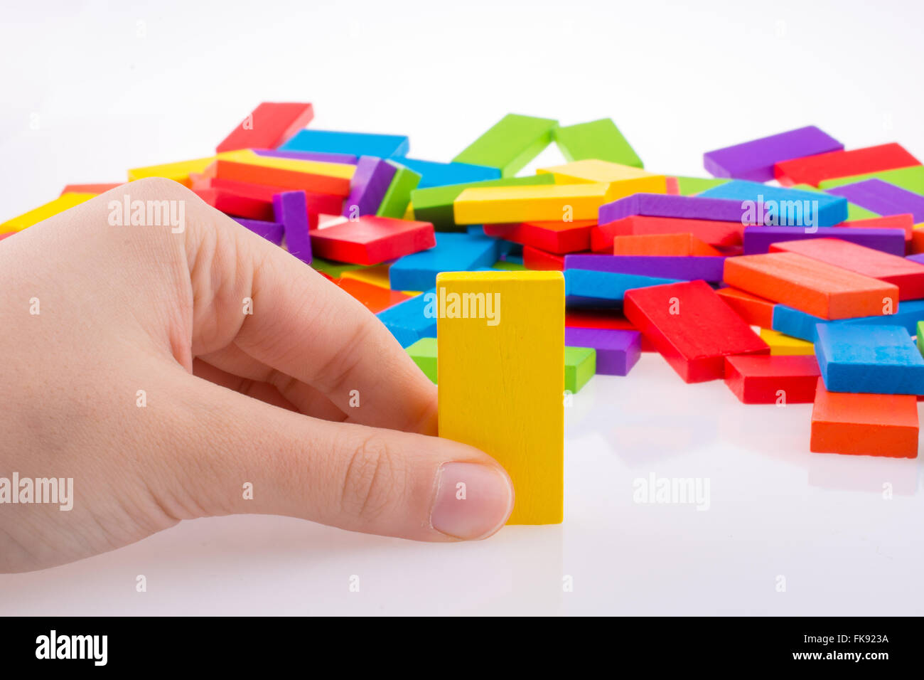 Hand playing with colored domino on white background Stock Photo - Alamy