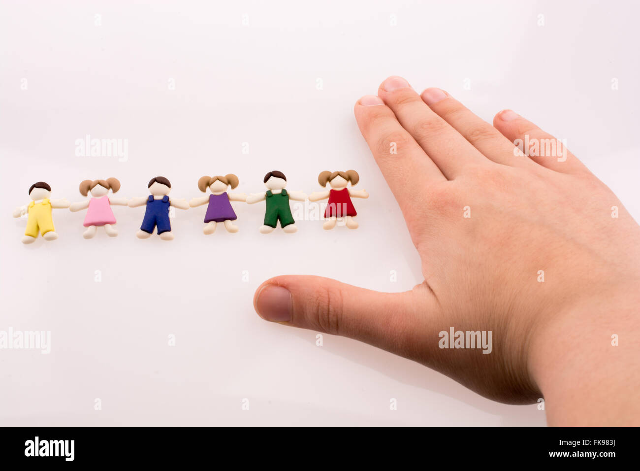 Hand near colorful dressed children figures on a white background Stock ...