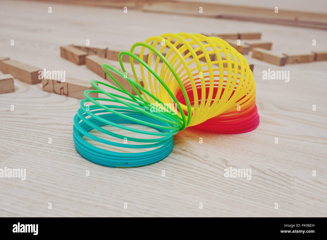 Rainbow spiral spring game on wooden background Stock Photo - Alamy