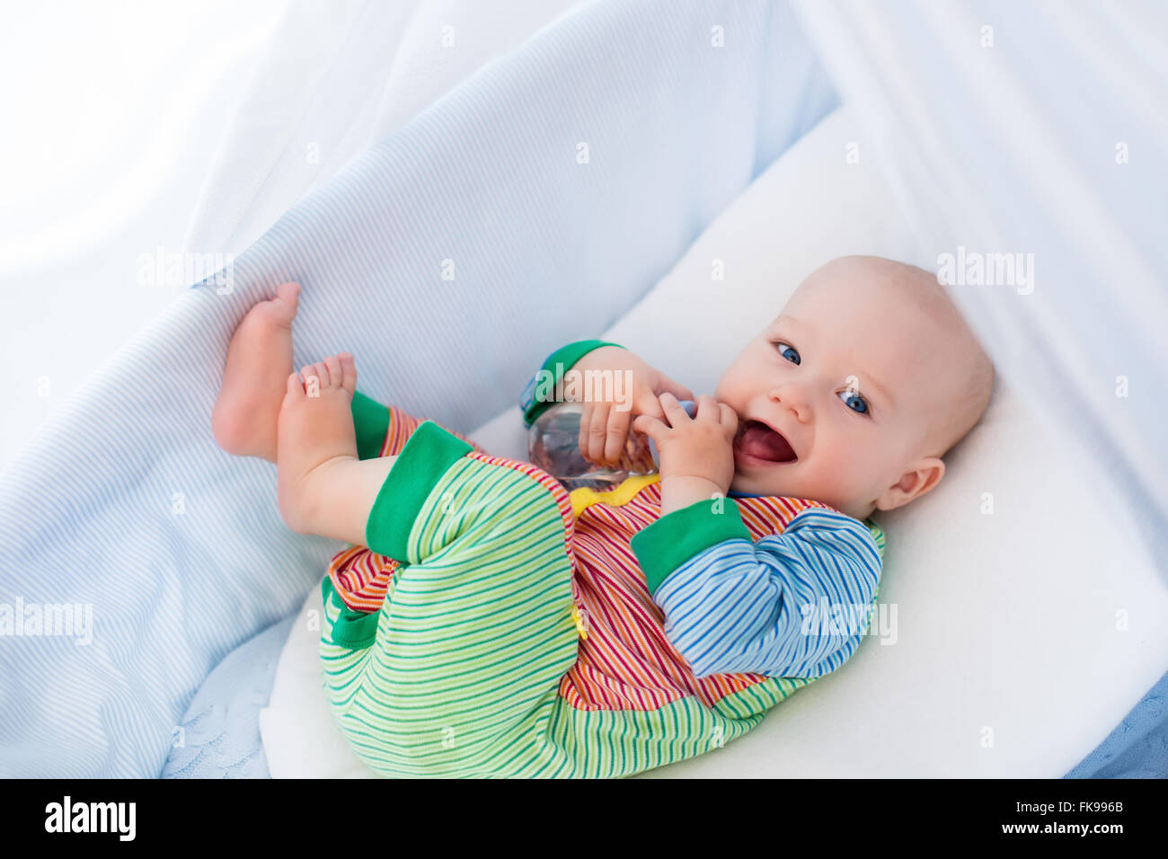 Funny baby in white crib with canopy. Nursery interior and bedding for ...