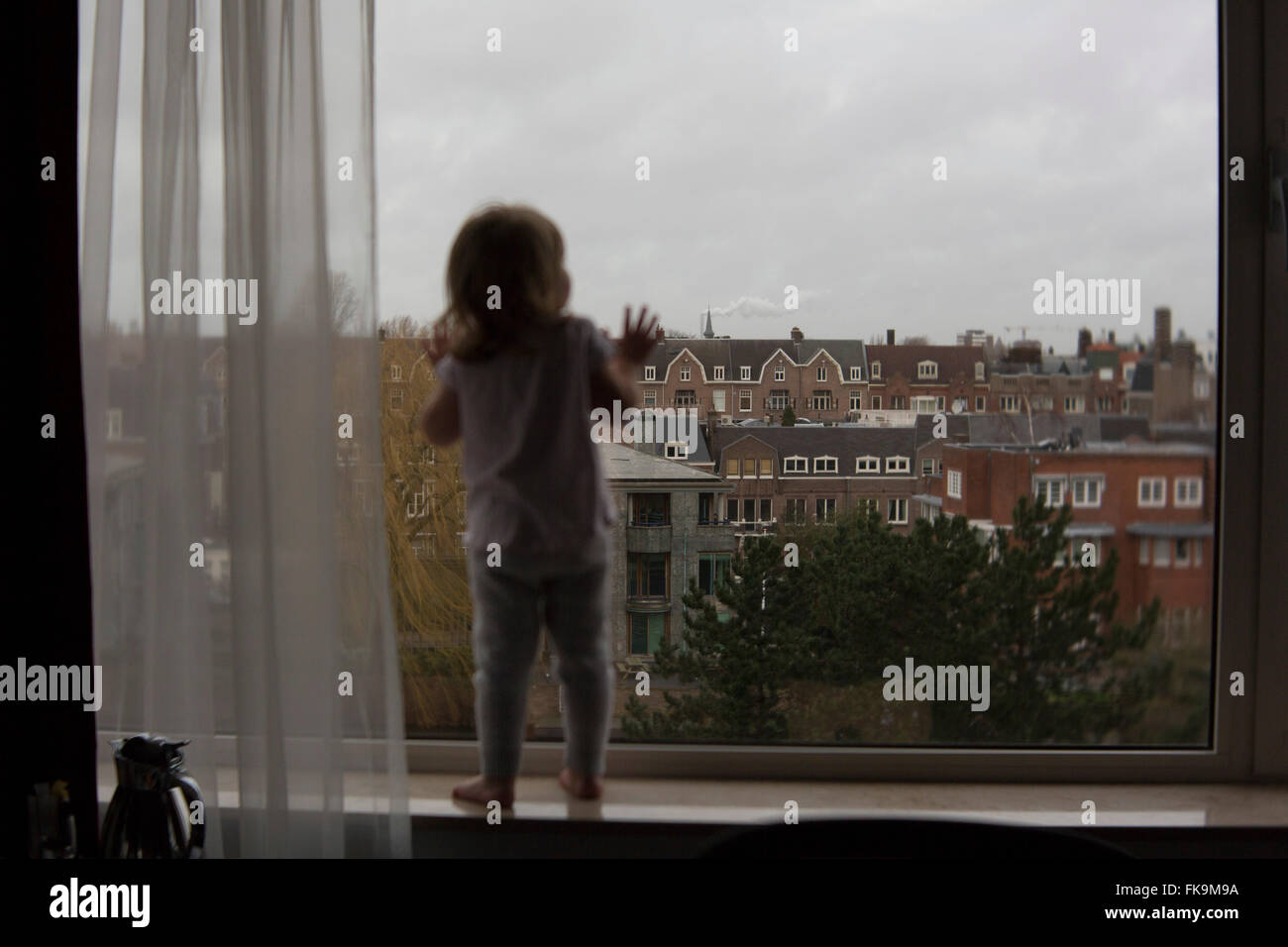 Toddler looking out of hotel room window with airplanes flying past ...