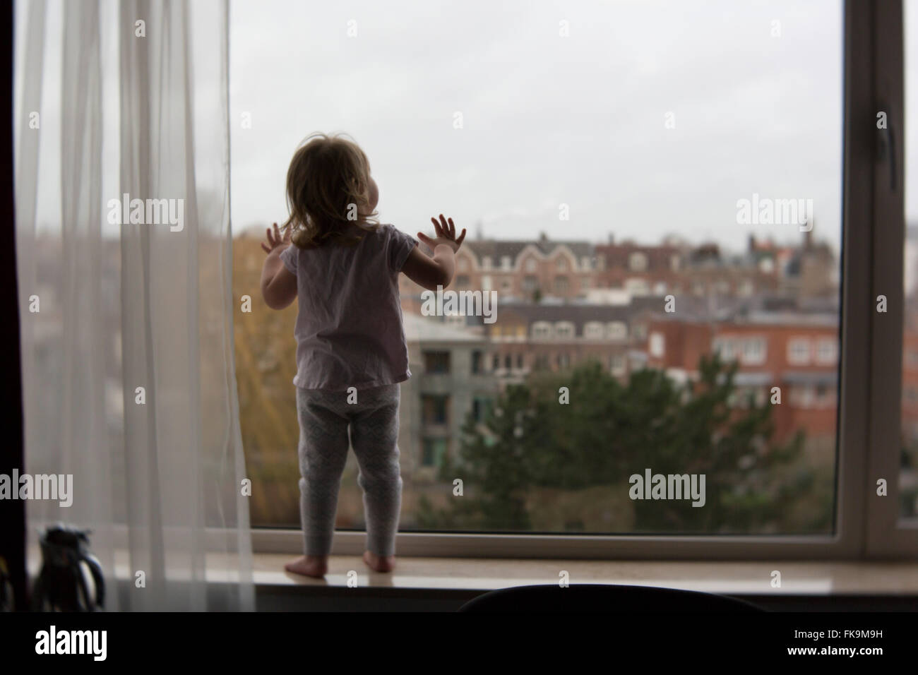 Toddler looking out of hotel room window with airplanes flying past ...