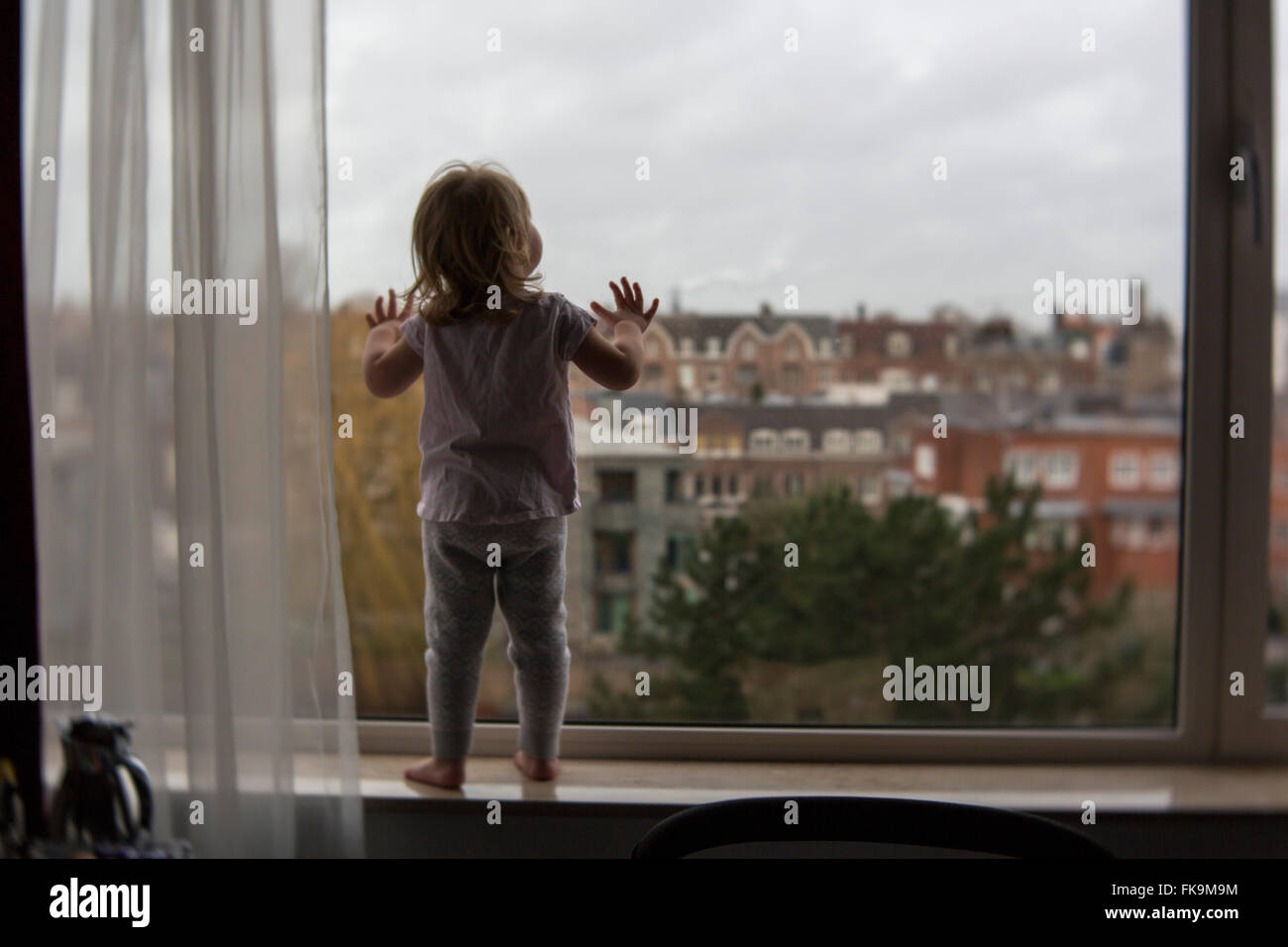 Toddler looking out of hotel room window with airplanes flying past ...