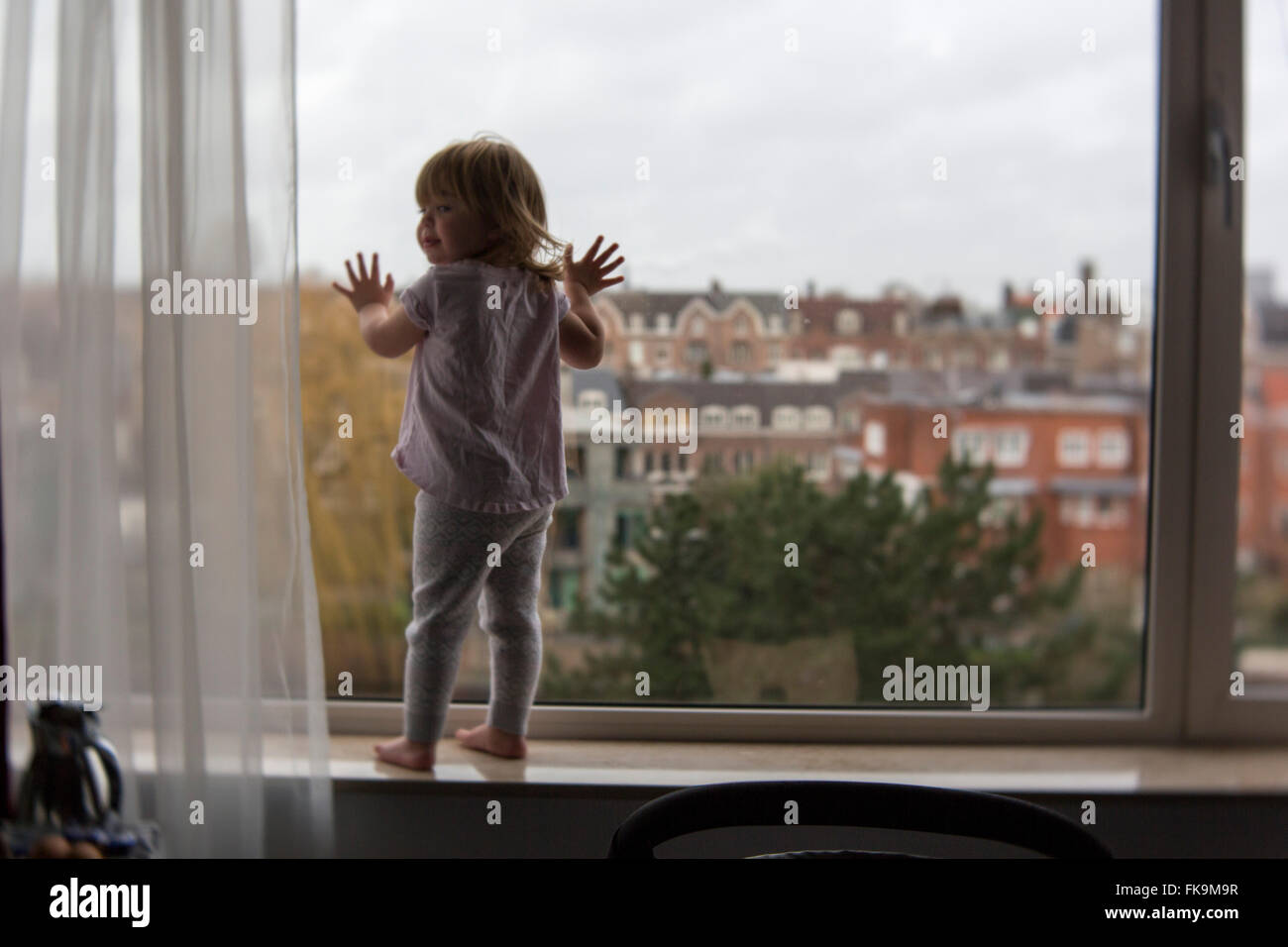 Toddler looking out of hotel room window with airplanes flying past ...