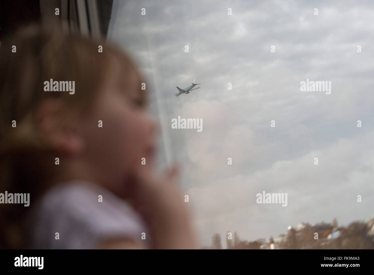 Toddler looking out of hotel room window with airplanes flying past ...