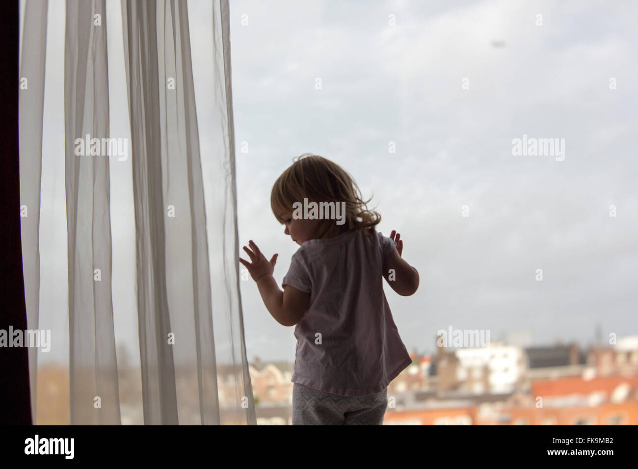 Toddler looking out of hotel room window with airplanes flying past ...