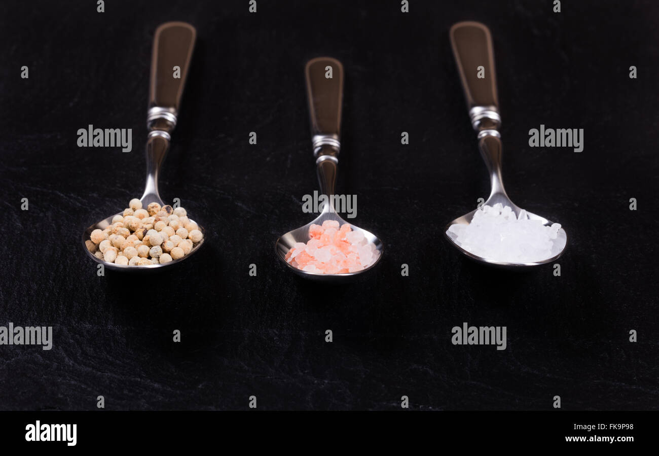 Close up three old spoons contains various spices on natural black ...