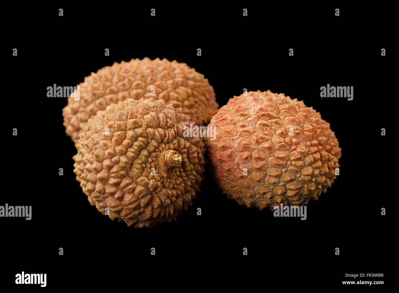 Three lychee fruits isolated on a black background Stock Photo - Alamy
