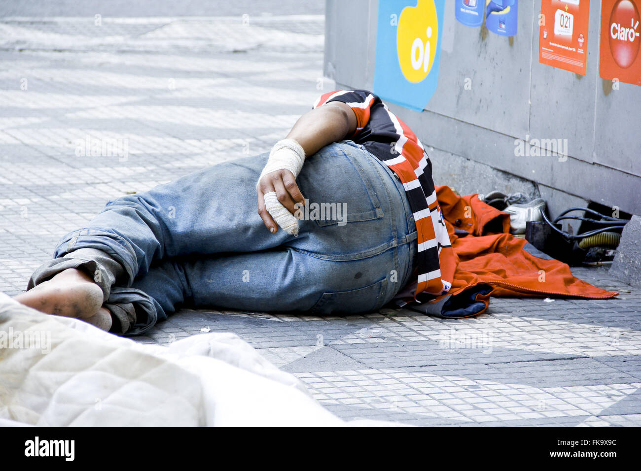 Homeless man with the bandaged wrist and finger sleeping on sidewalk ...