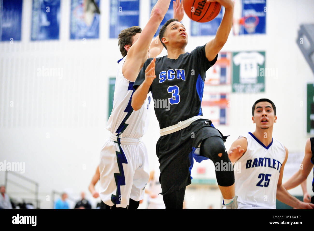 A high school player trying to get off a shot while a defender attempts ...