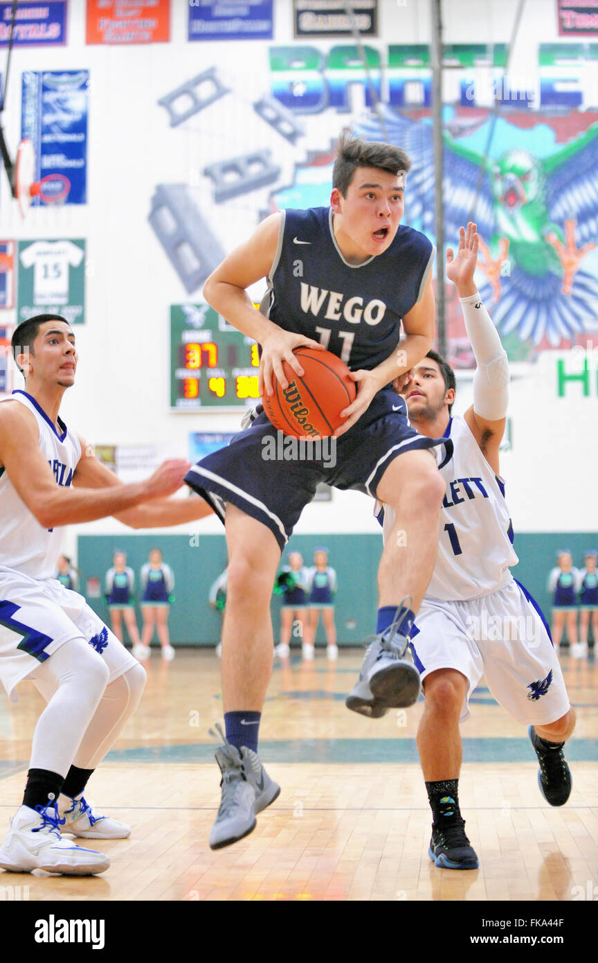 Player pulling down a rebound in the midst of two opponents during a ...