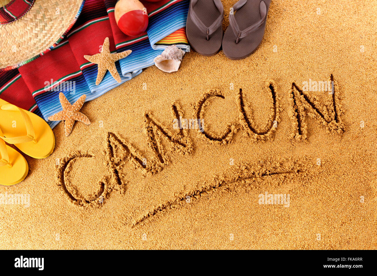 The word Cancun written in sand on a Mexican beach, with sombrero ...