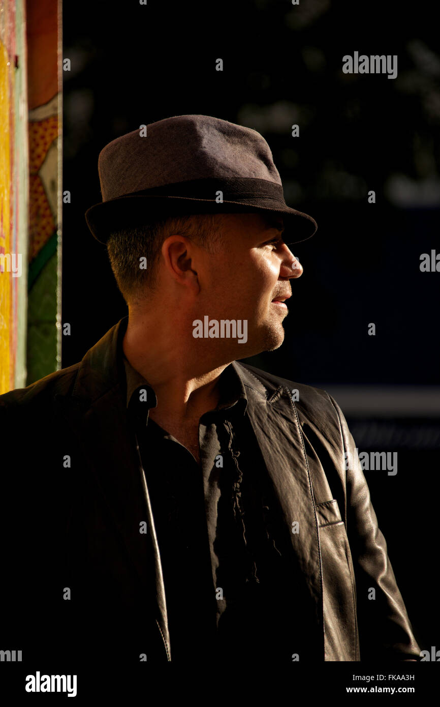 Sunlit man in hat against dark background Stock Photo - Alamy