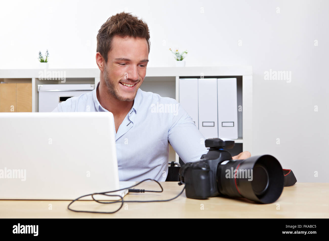 Happy photographer downloading photos from camera to laptop computer ...