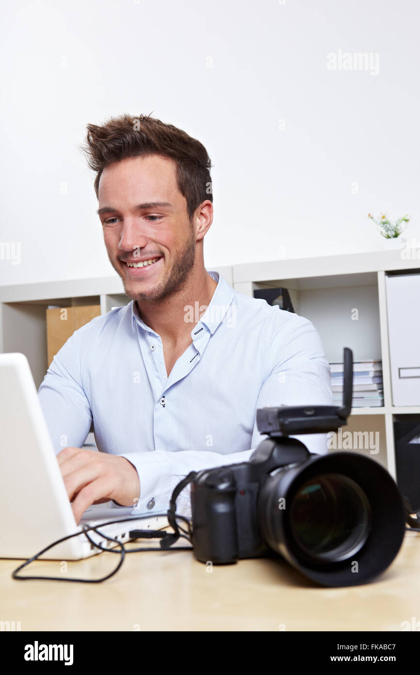 Professional photographer with camera and laptop computer in office ...