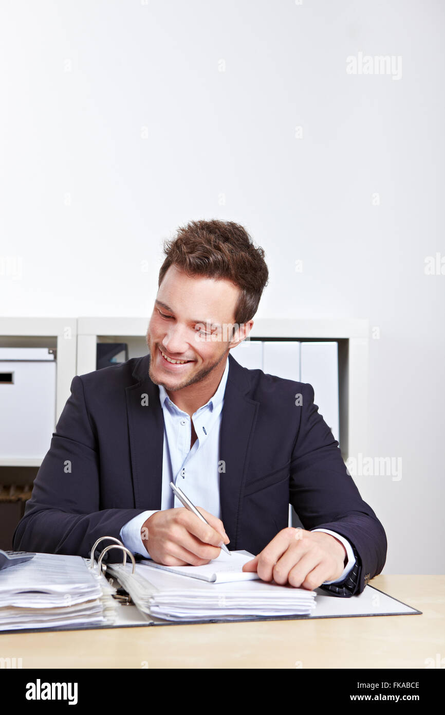 Happy business man taking notes in files in office Stock Photo - Alamy