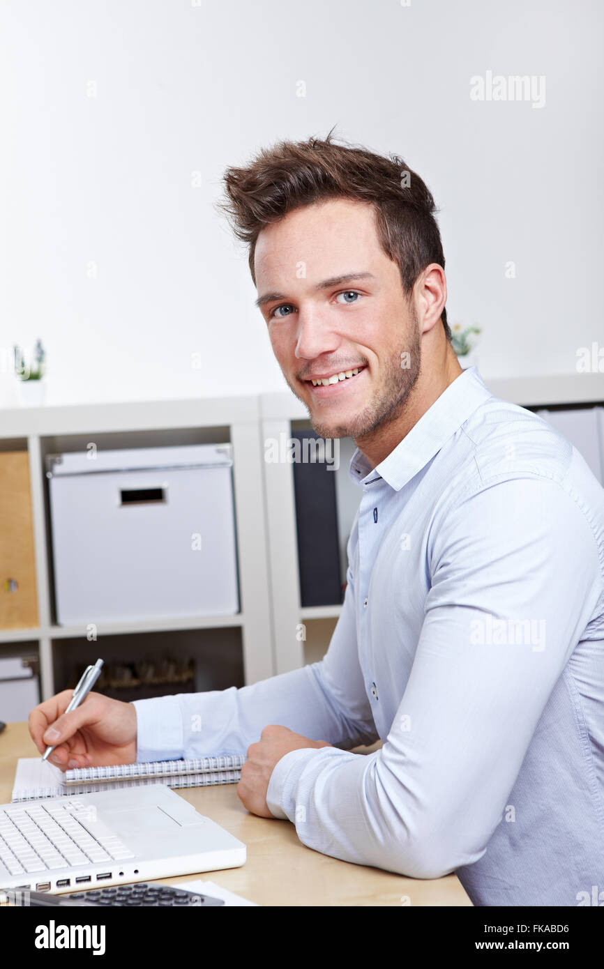 Happy college student learning at desk with laptop computer Stock Photo ...