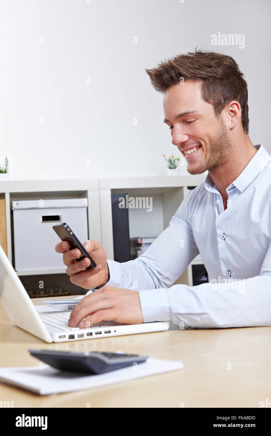 Business man connecting cell phone and computer wireless via bluetooth ...